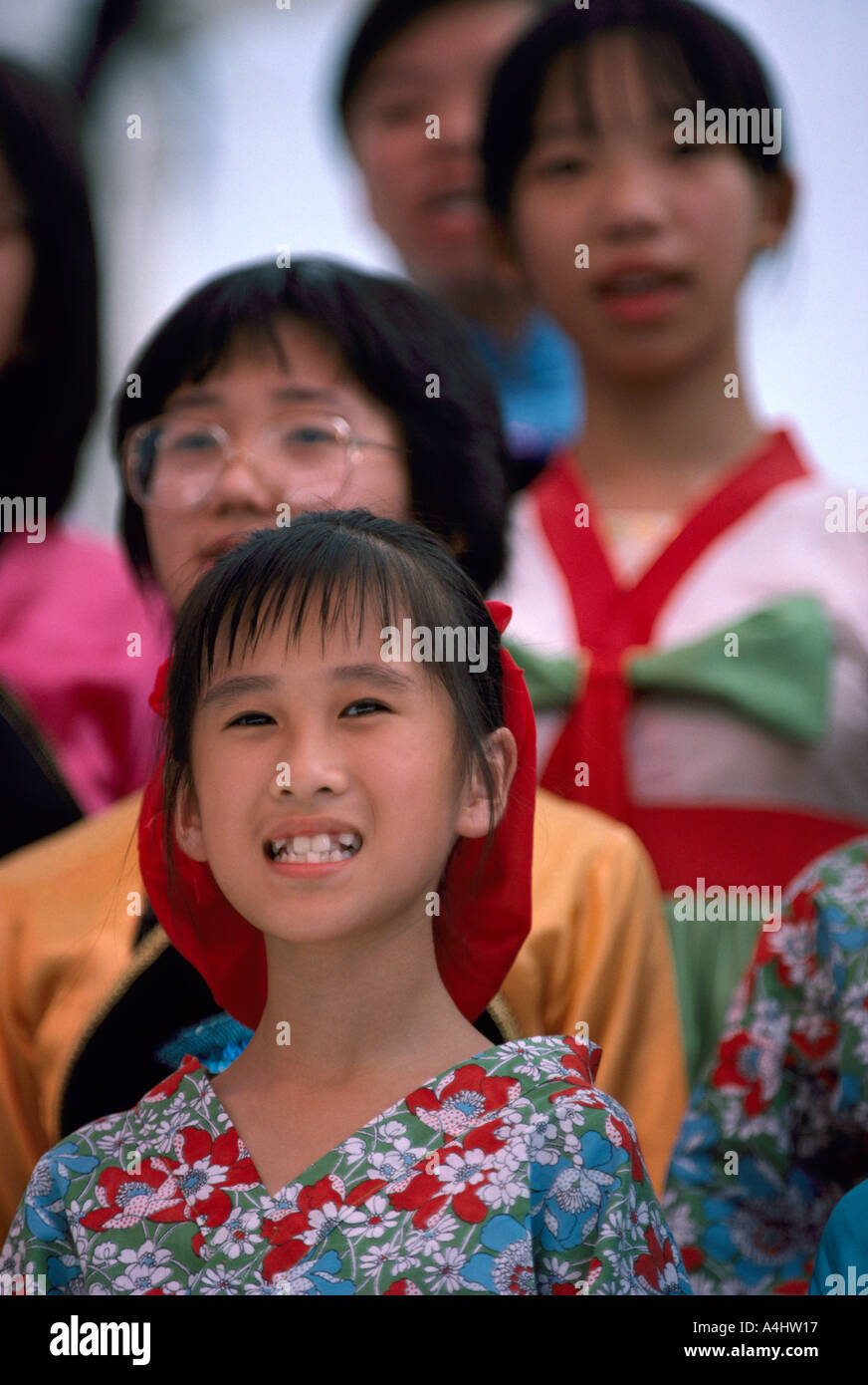 A Young Chinese Girl stands in front of a Group of Chinese People in ...