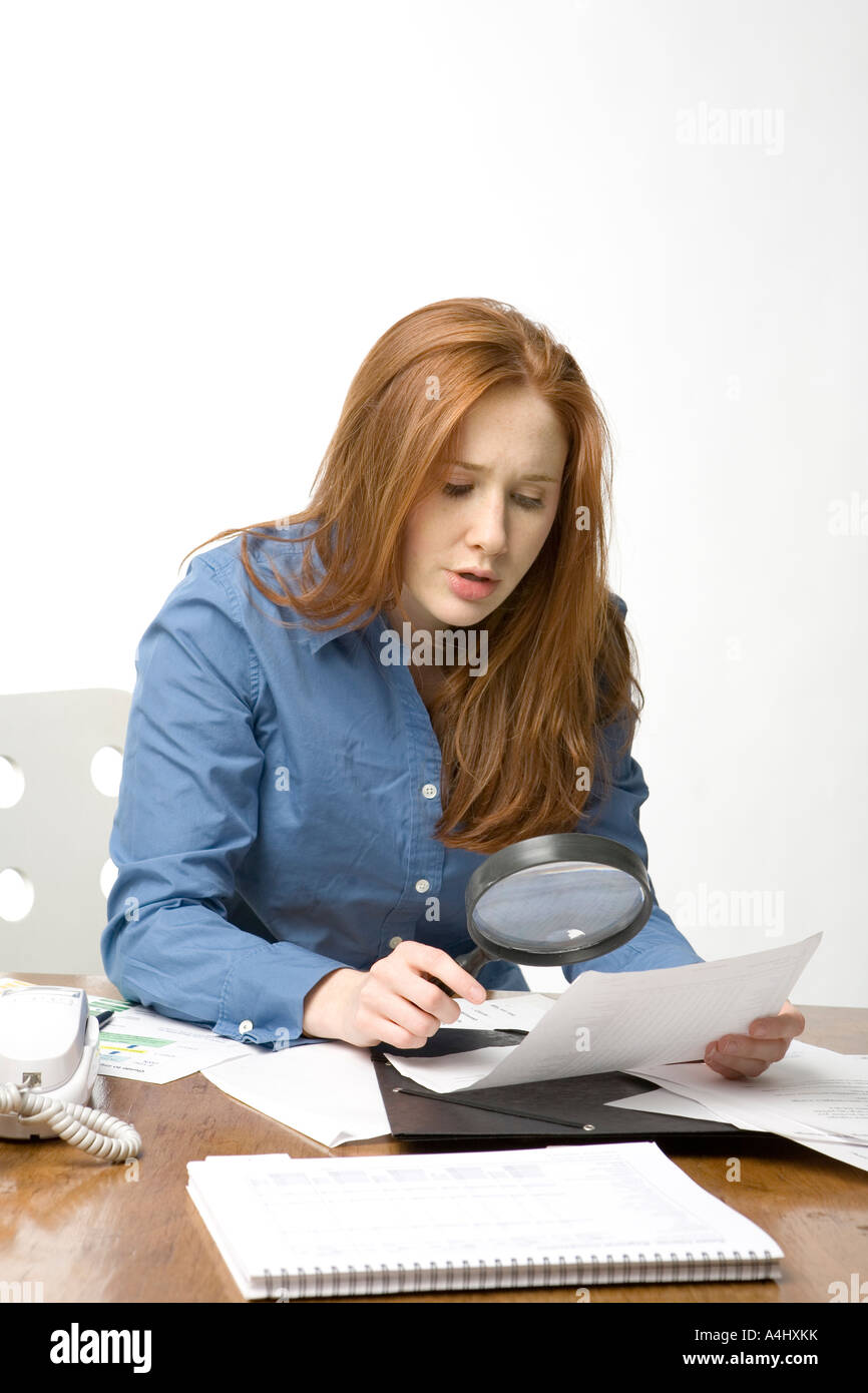 Woman examining a document with a magnifying glass Stock Photo - Alamy