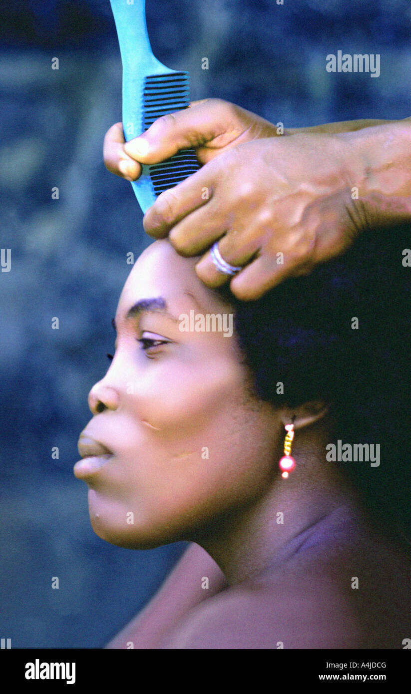 On West Africa's Gold Coast a neighbor grooms a young woman's hair in a ...