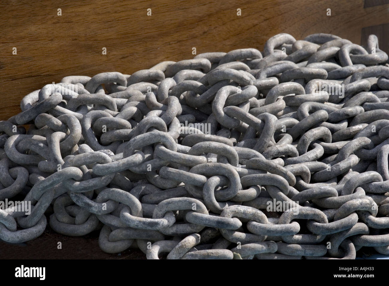 Section of chain by a wooden boat Stock Photo - Alamy