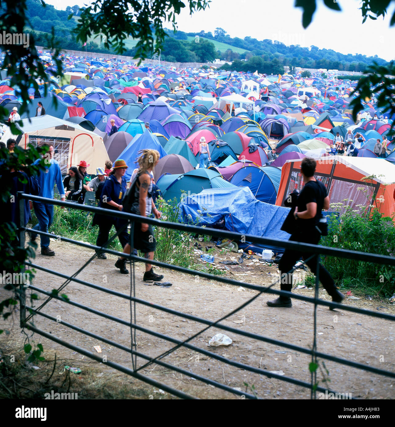 People walking past tents and gate on the Worthy Farm camping site at ...