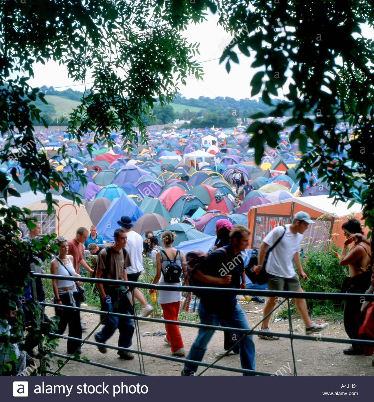 People walking past tents and gate on the Worthy Farm camping site at ...