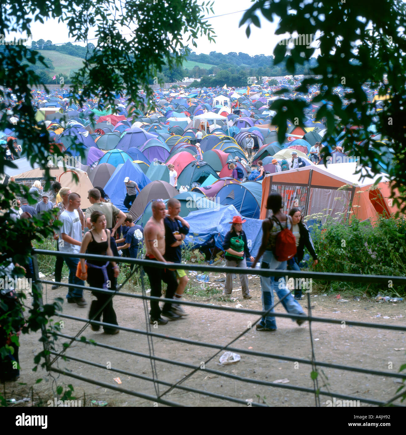 People walking past tents and gate on the Worthy Farm camping site at ...