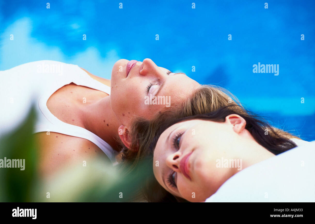 Two young women resting on a poolside Stock Photo - Alamy