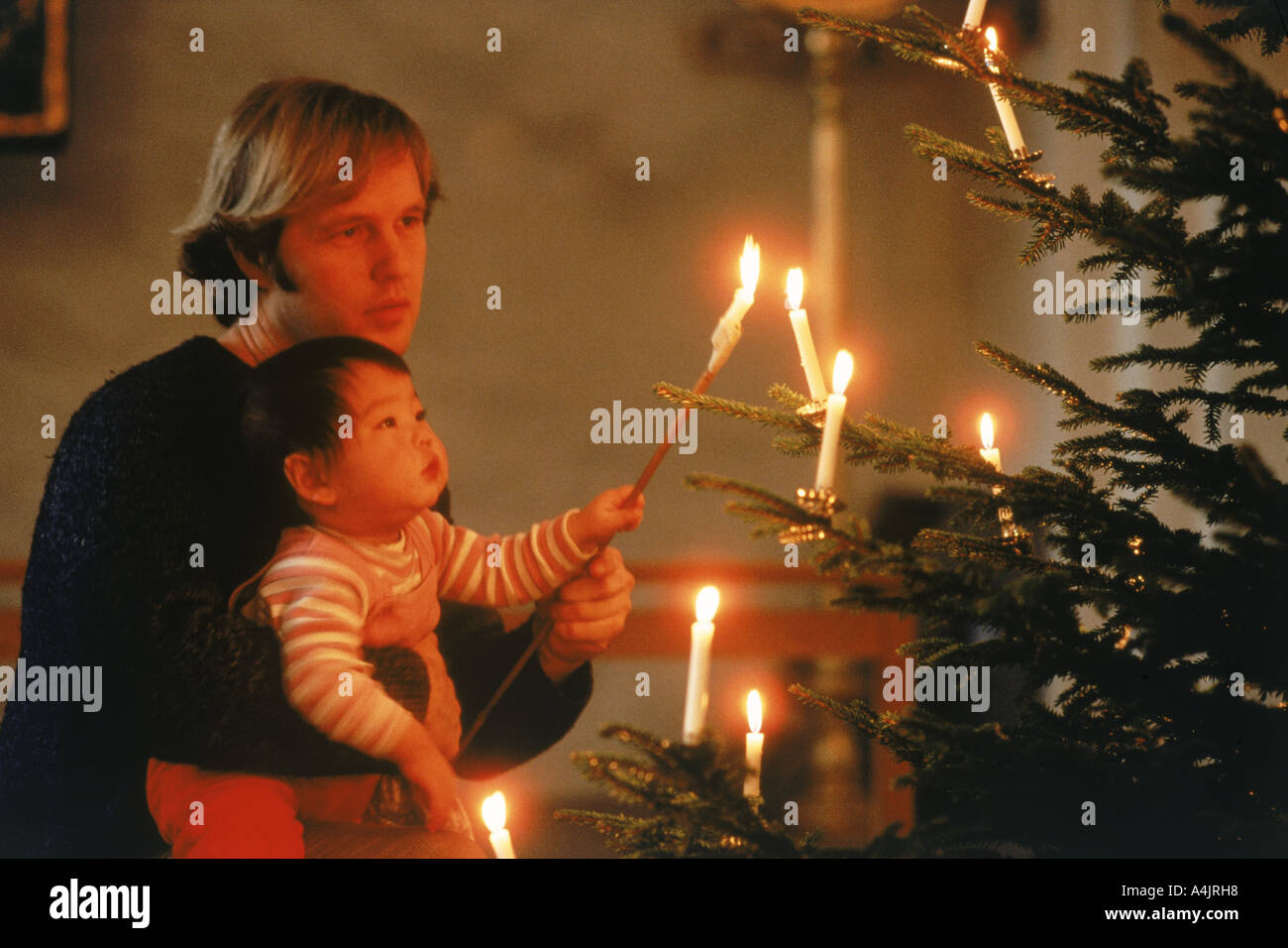 Dad with child lighting candles on family Christmas tree Stock Photo ...