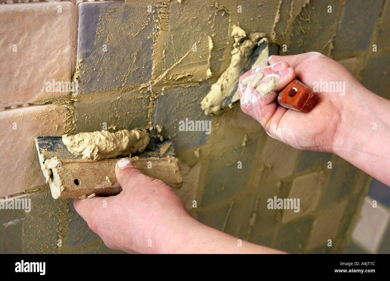 APPLYING GROUT IN A BATHROOM WITH PILKINGTON TILES Stock Photo - Alamy