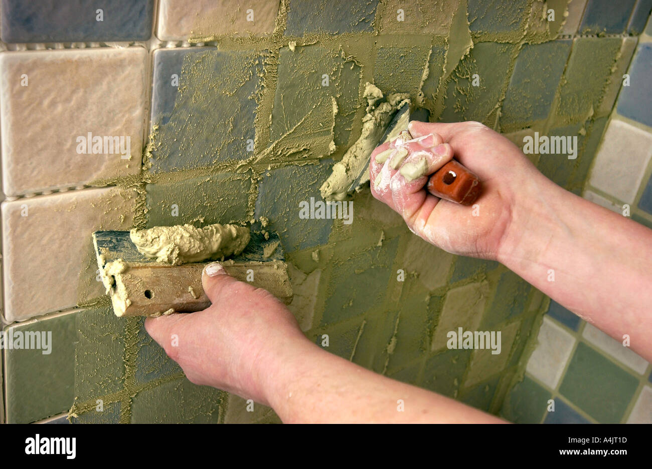 APPLYING GROUT IN A BATHROOM WITH PILKINGTON TILES Stock Photo - Alamy