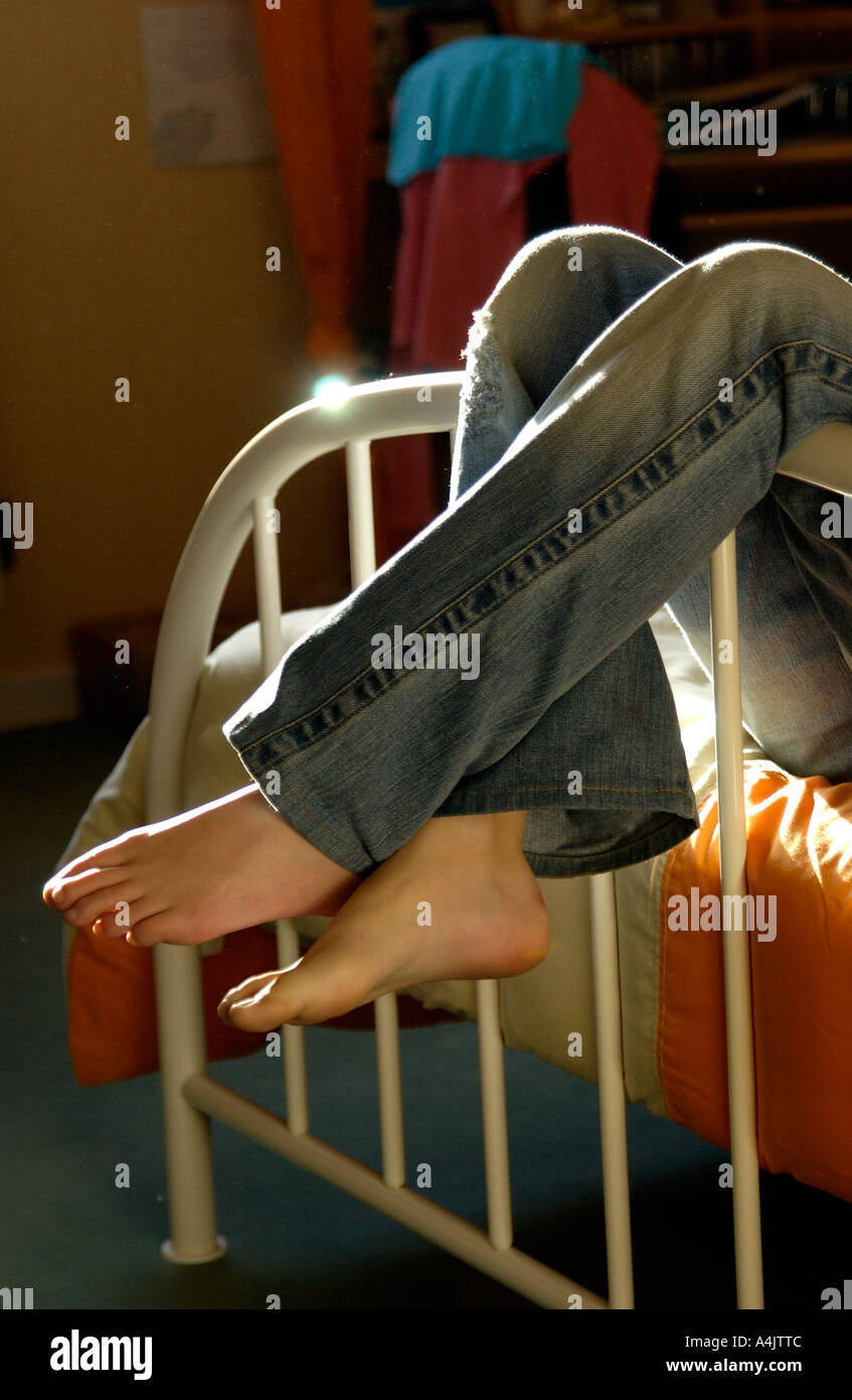 Relaxation - teenager with legs over the end of the bed in the bedroom ...