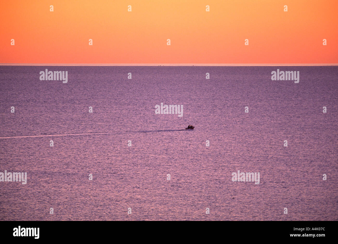 Motor boat driving at sea at dusk Stock Photo - Alamy