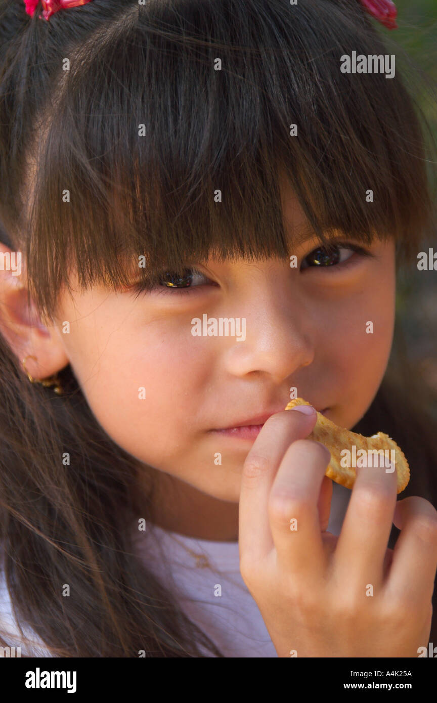 Hispanic young girl portrait girl eating cracker Stock Photo - Alamy
