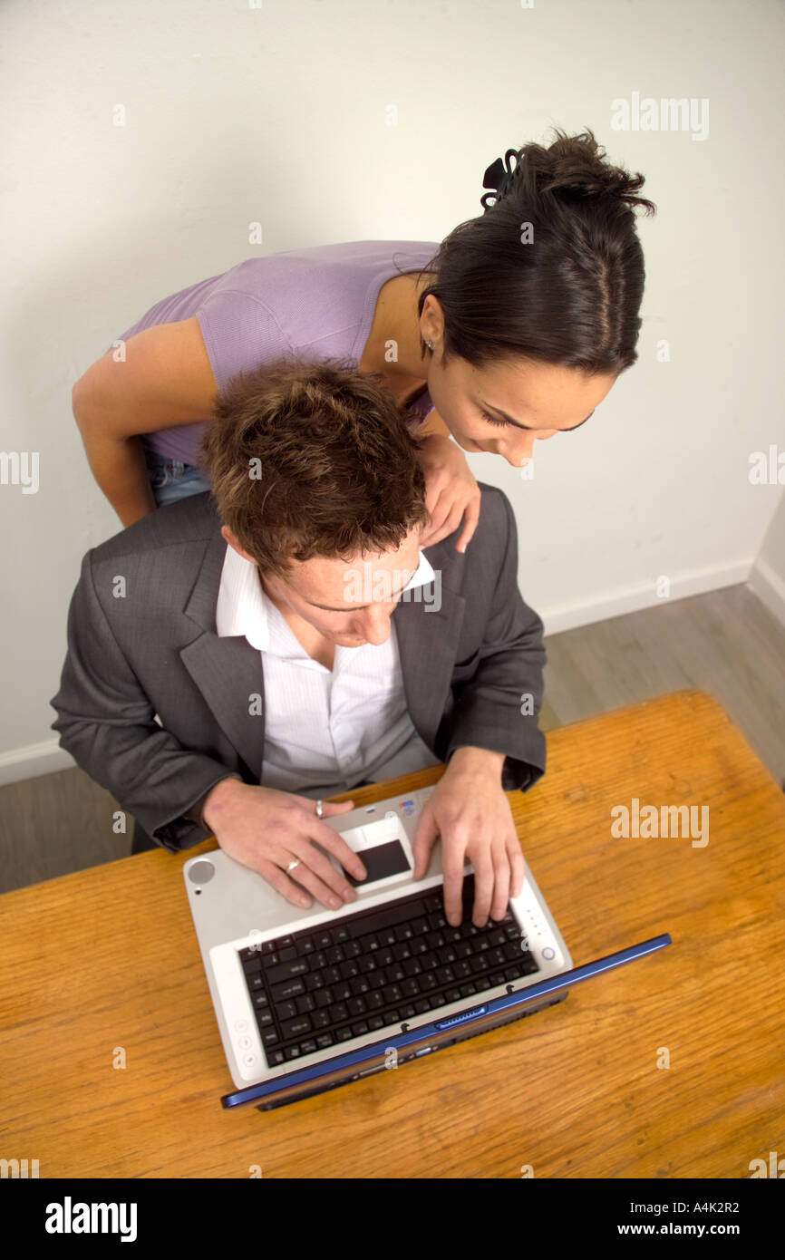 man with a women looking over his shoulder working at a laptop computer ...