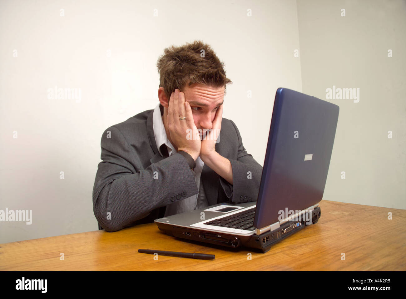 man sitting at a computer with hands on his face Stock Photo - Alamy
