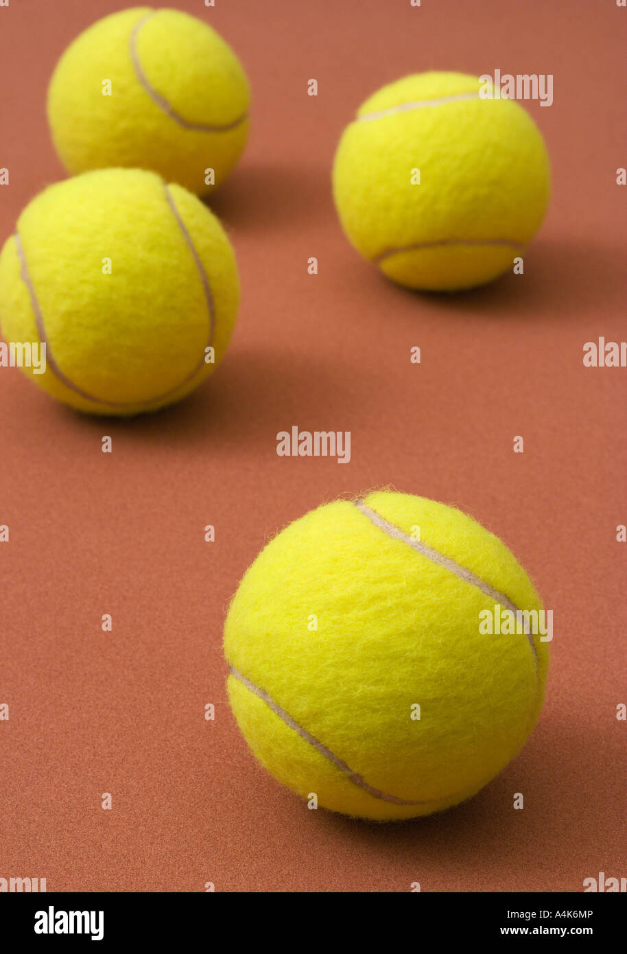 Yellow tennis balls isolated on a red ochre background Stock Photo - Alamy