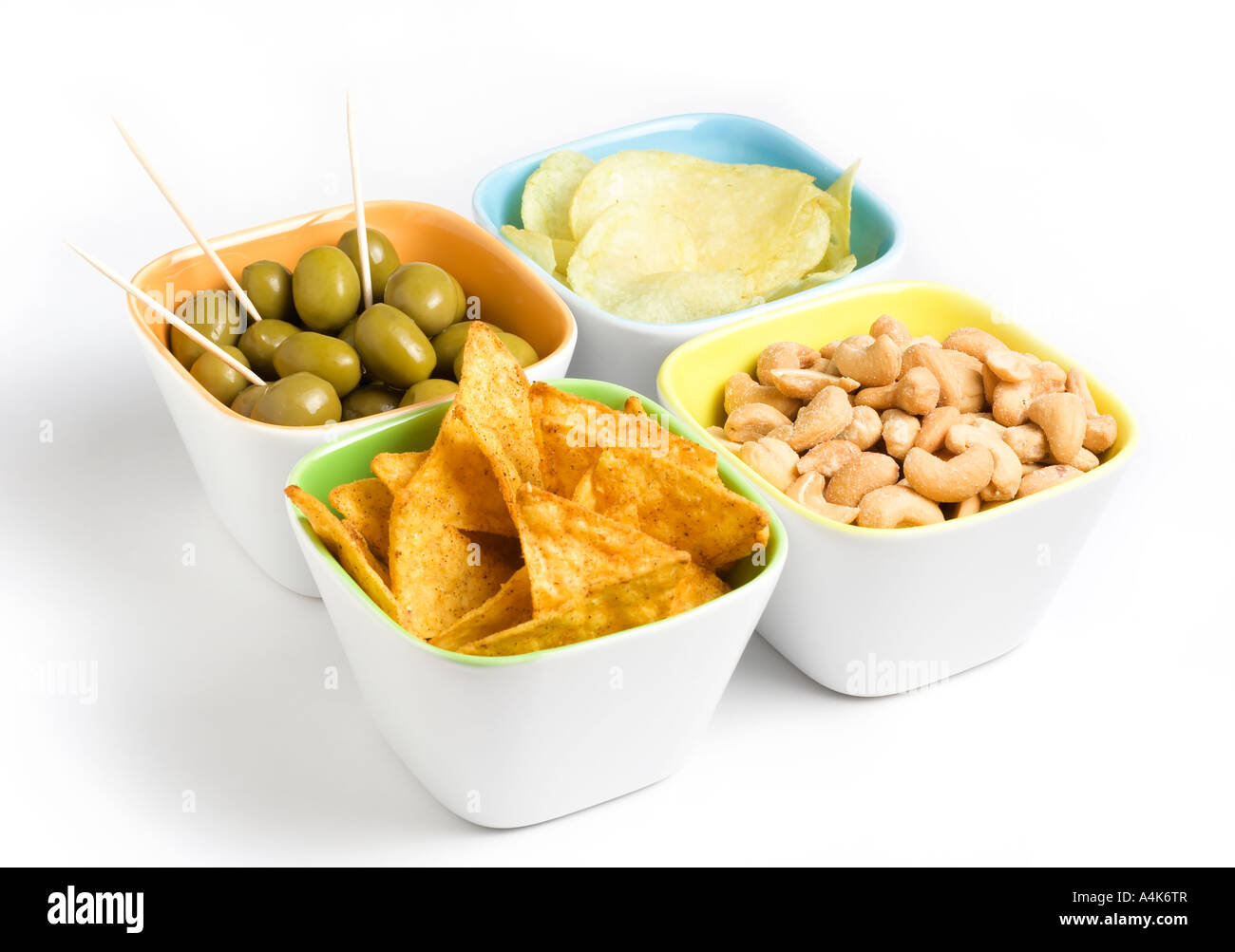 Four cups of appetizers (olives, cashew nuts, potato chips and tortilla ...
