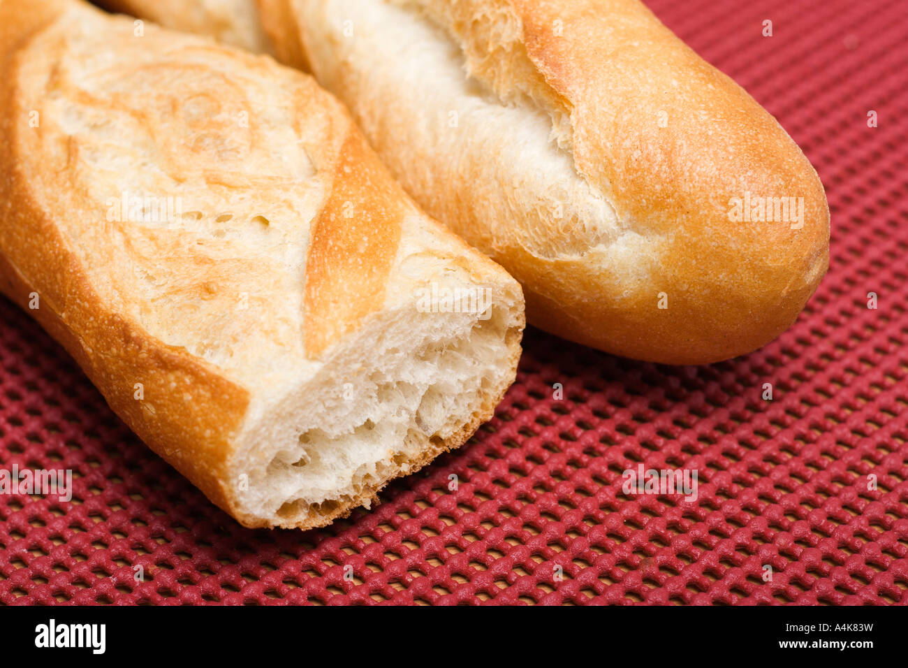 Closeup view of two french bread baguettes on a red tablemat (shallow ...