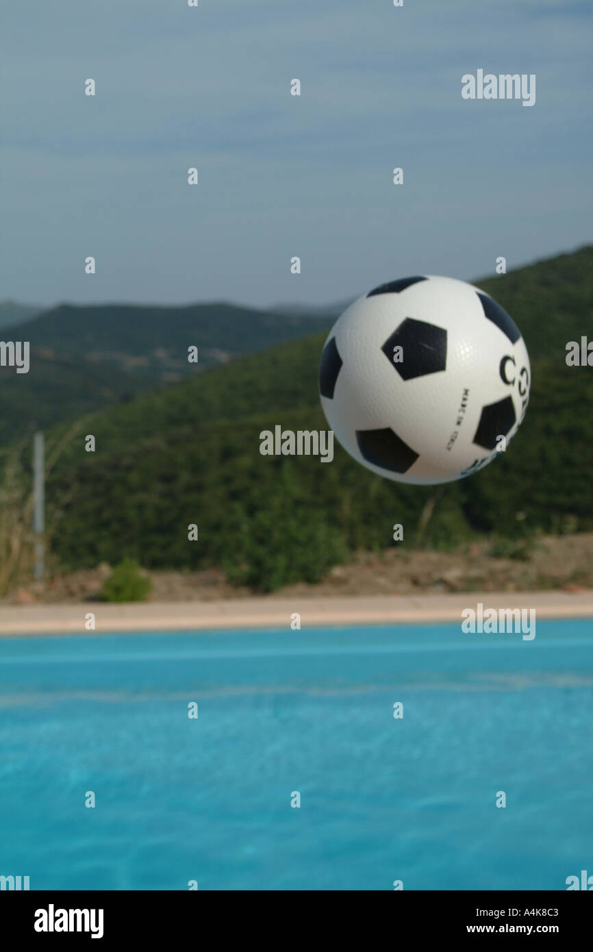Football suspended in mid air above swimming pool and landscape Stock ...