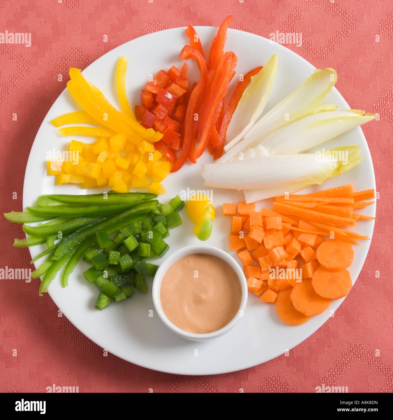 An appetizer plate with sliced vegetables and a cup of tomato ...