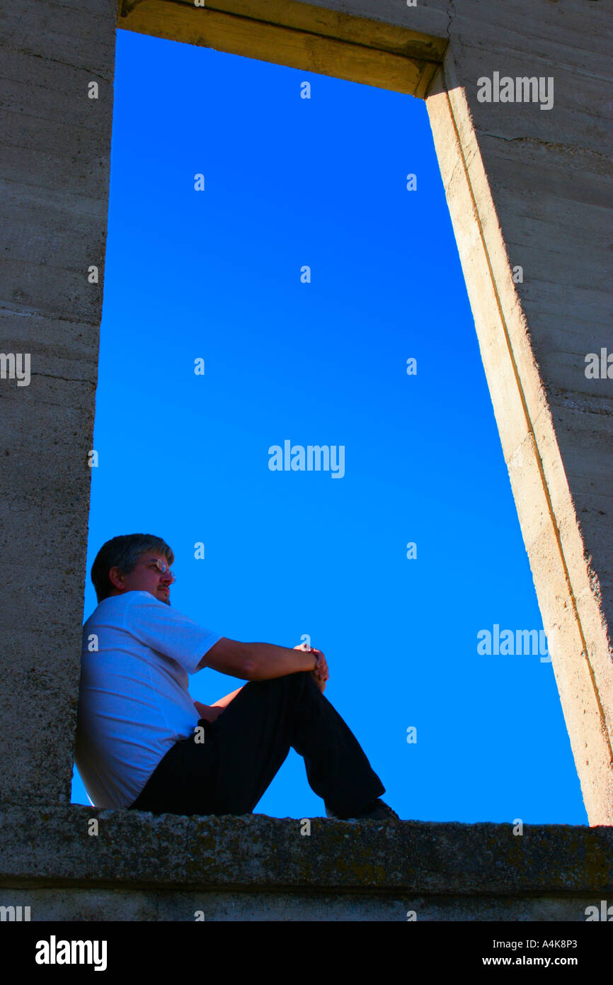 Man sitting on open ledge Stock Photo - Alamy