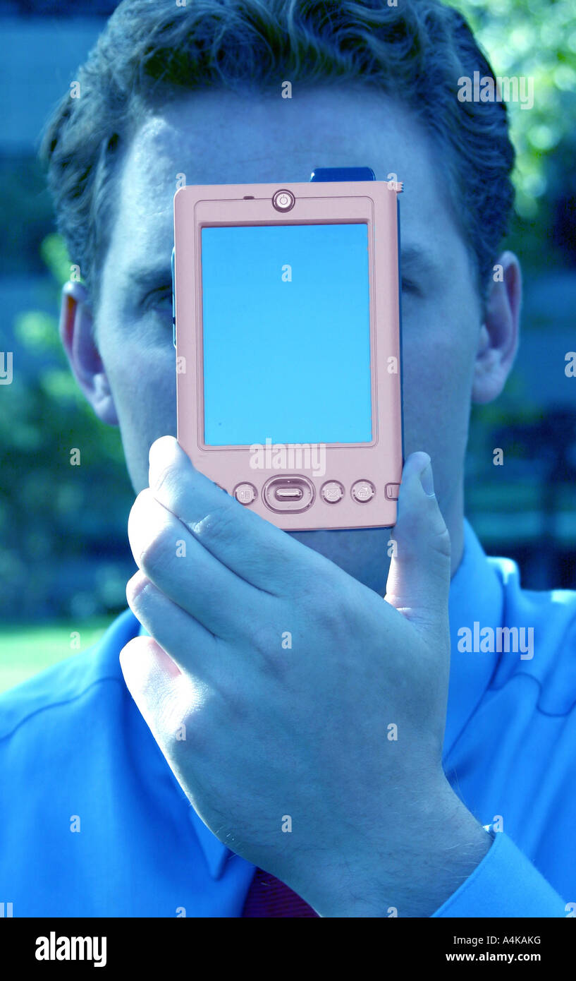 Businessman holds up PDA with blue screen in front of his face which is ...