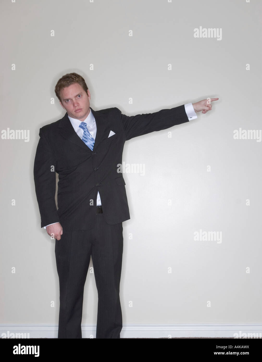 Businessman standing and points with his arm raised and finger pointed ...