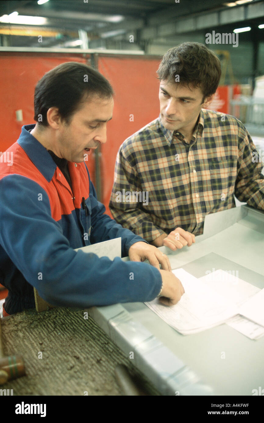 Manual worker and apprentice at work table Stock Photo - Alamy