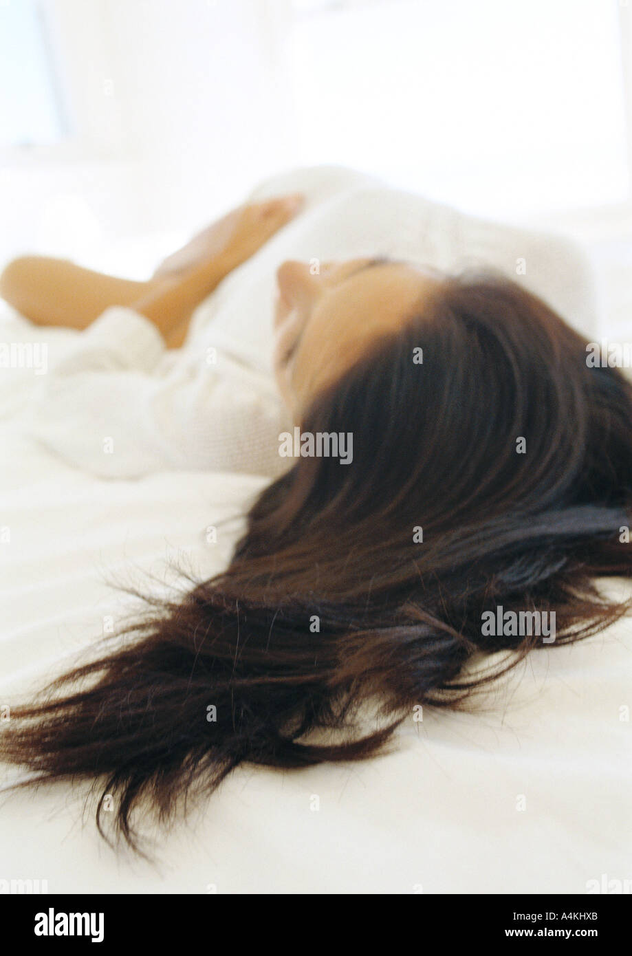 Young woman lying on bed Stock Photo - Alamy