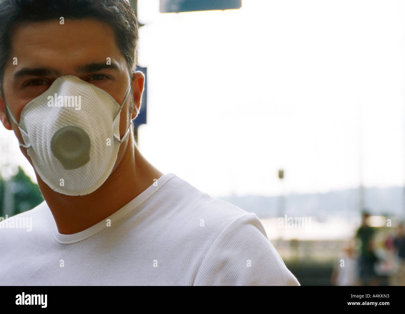 Man wearing white dust mask over nose and mouth, blurred background ...