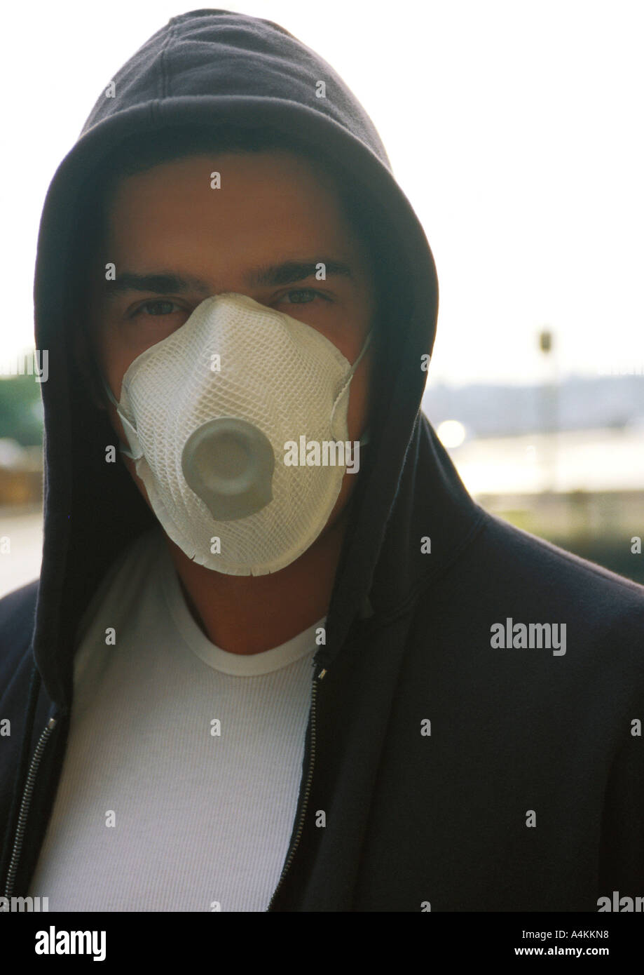 Man wearing hooded sweatshirt and white dust mask over nose and mouth ...