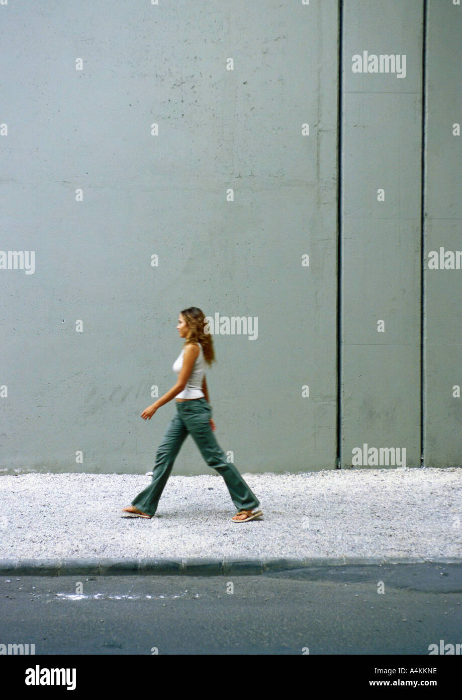 Woman walking on sidewalk, side view Stock Photo - Alamy