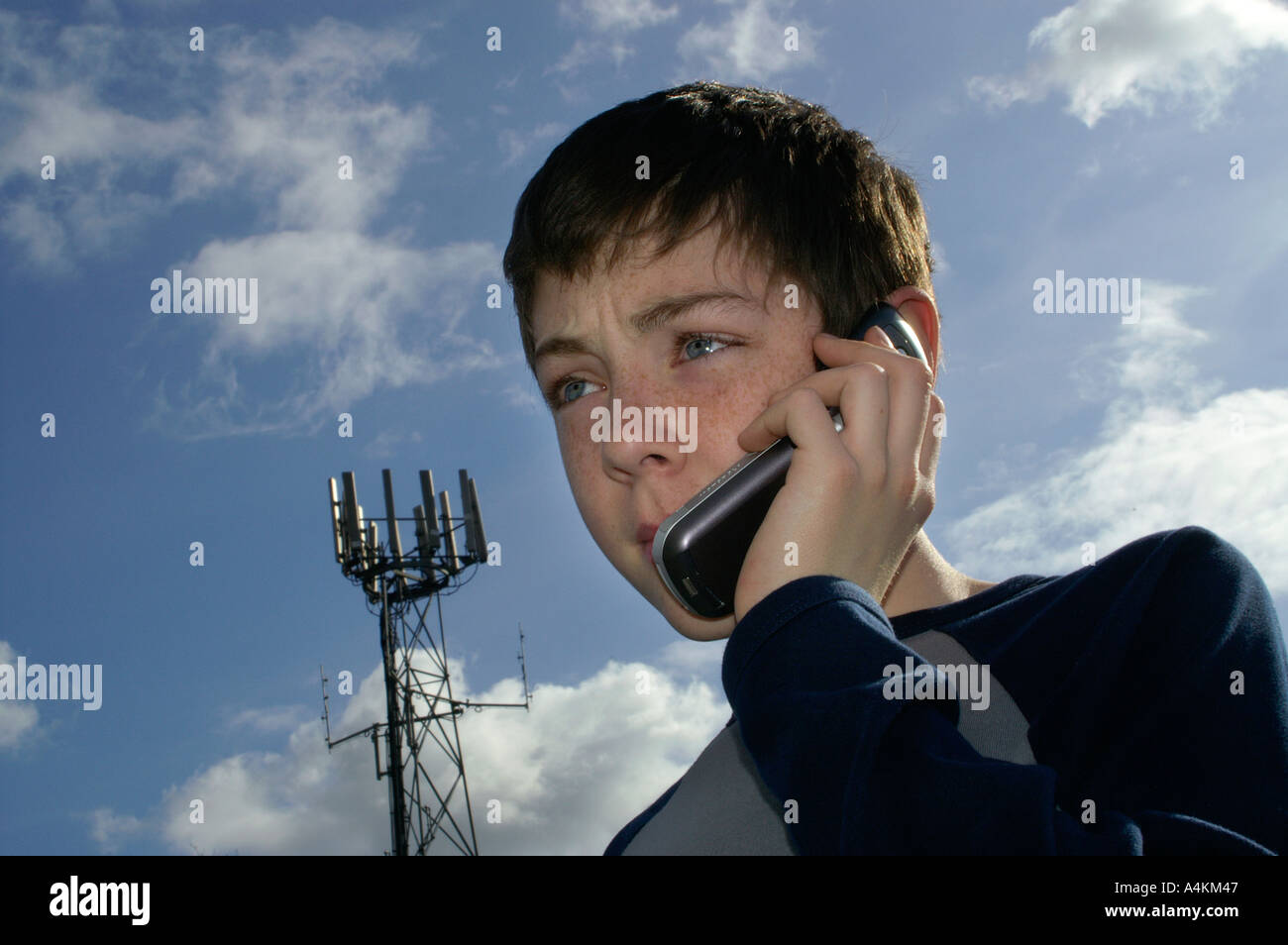 12 year old boy holding 3G mobile handset with mobile phone mast in ...