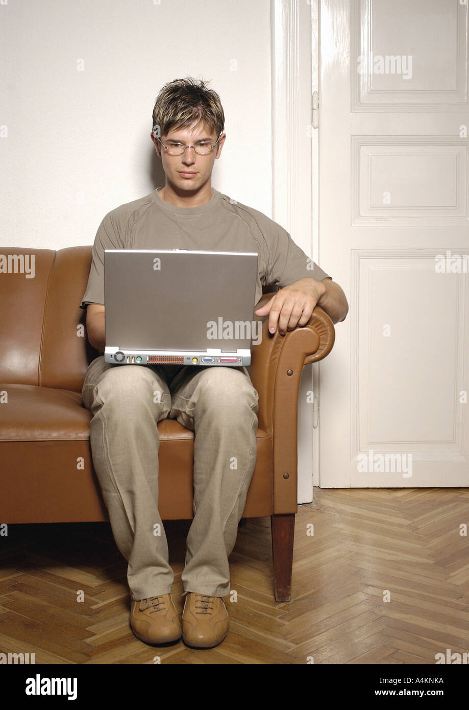 Man sitting on sofa, using laptop computer Stock Photo - Alamy