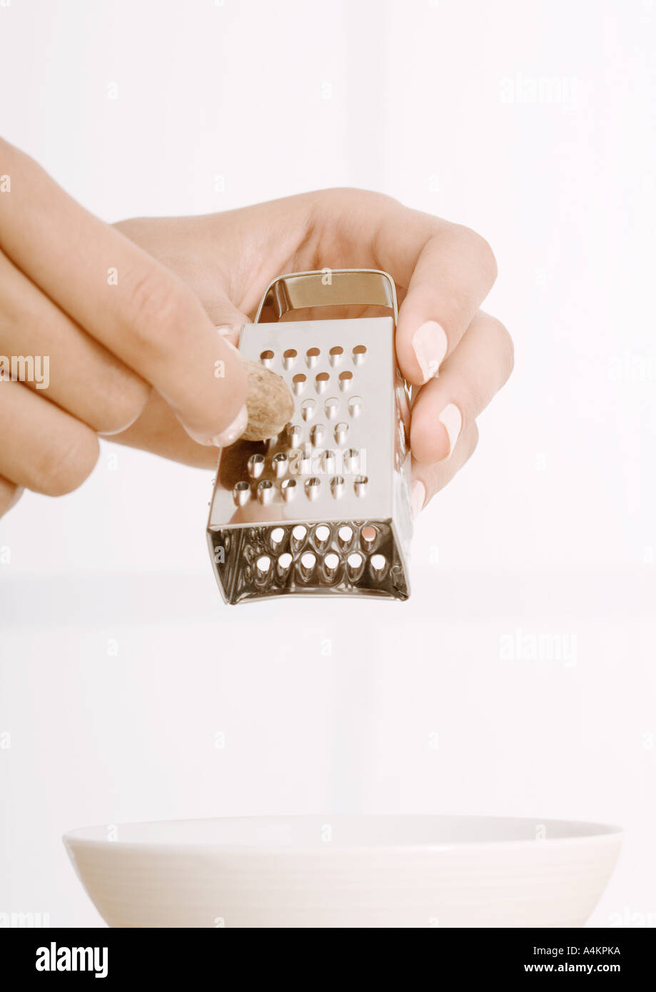Woman's hand grating nutmeg into bowl Stock Photo - Alamy