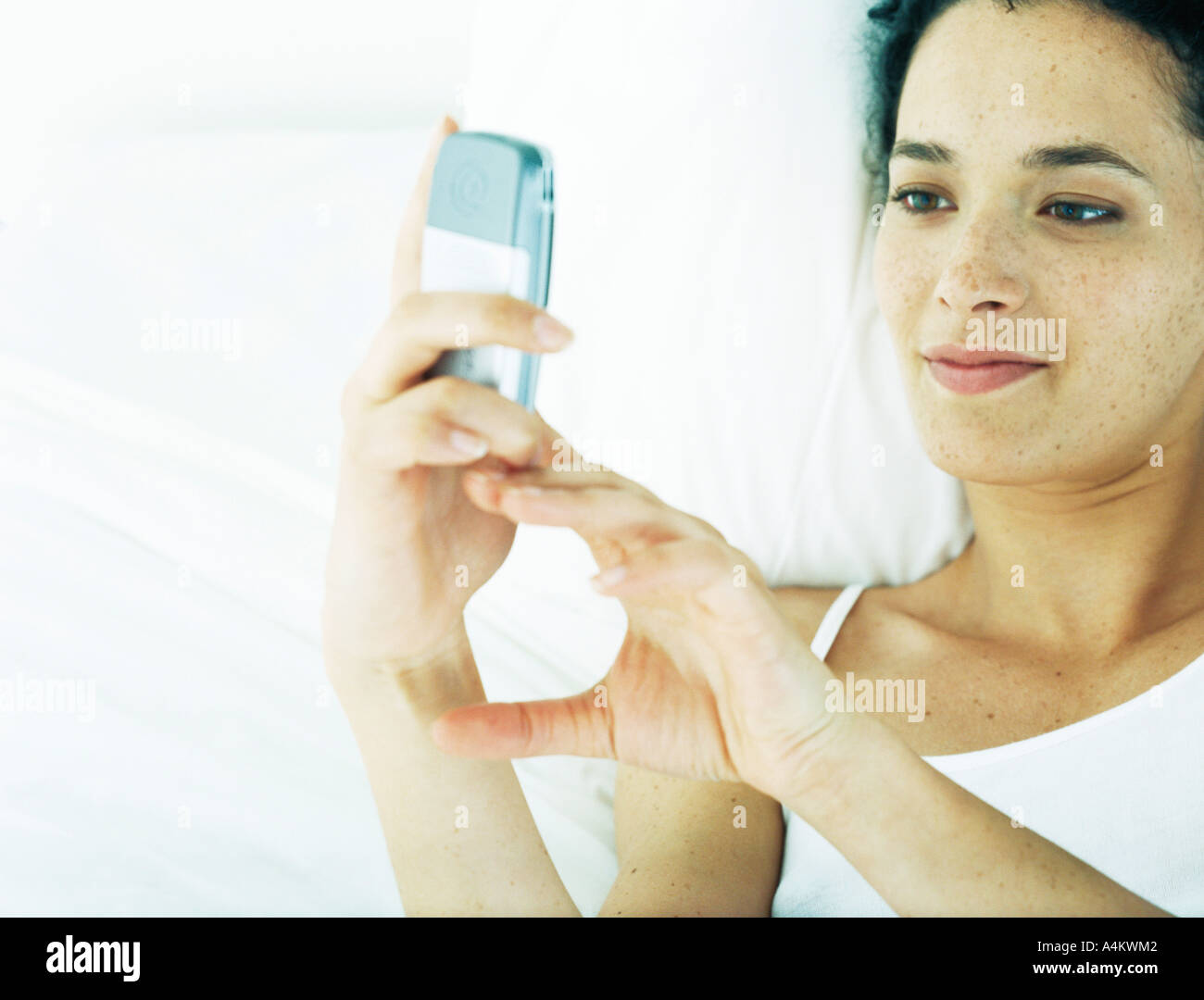 Woman lying on back on bed, looking at cell phone Stock Photo - Alamy