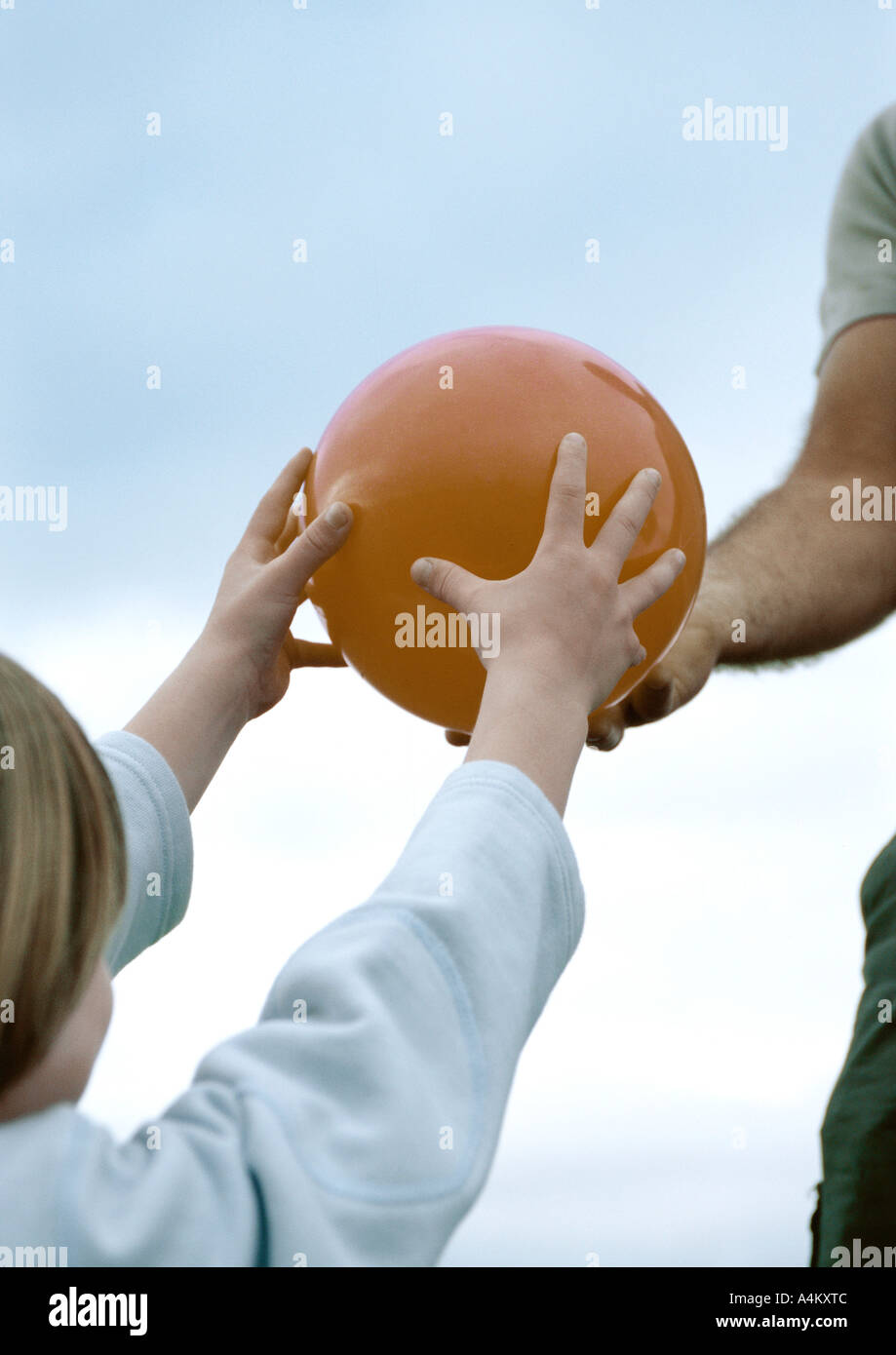 Boy taking ball from father, partial view Stock Photo - Alamy