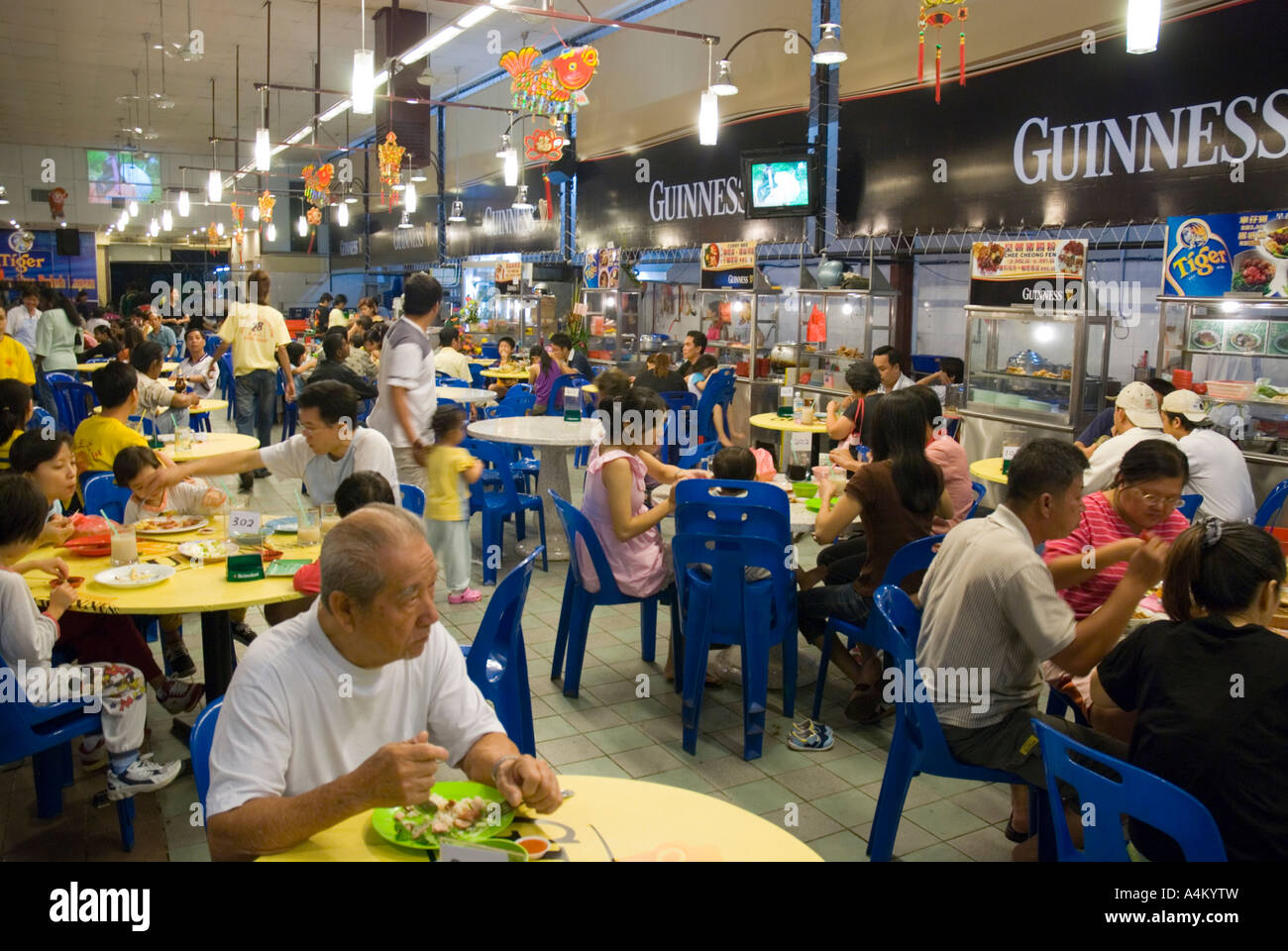 A bustling food court with Guinness advertising in Ipoh Malaysia Stock ...