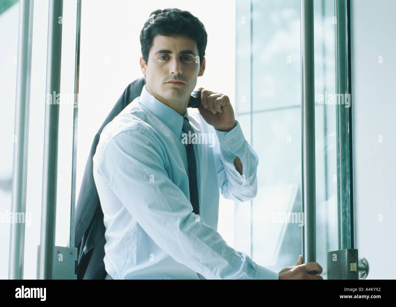 Businessman holding suit jacket over shoulder, coming through door ...