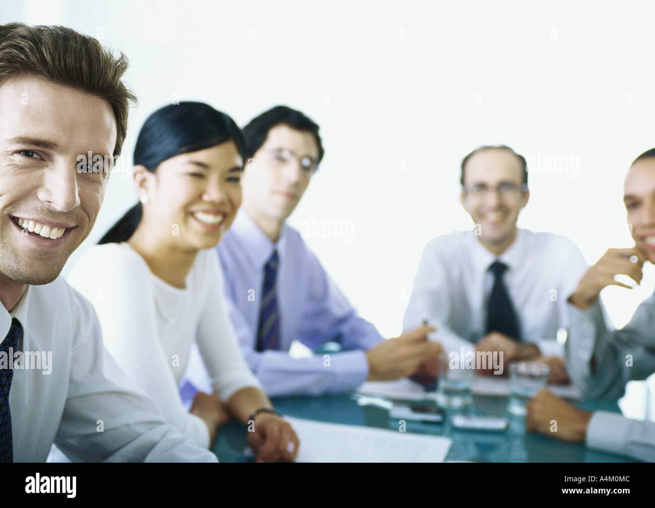 Businesspeople sitting around table, smiling Stock Photo - Alamy