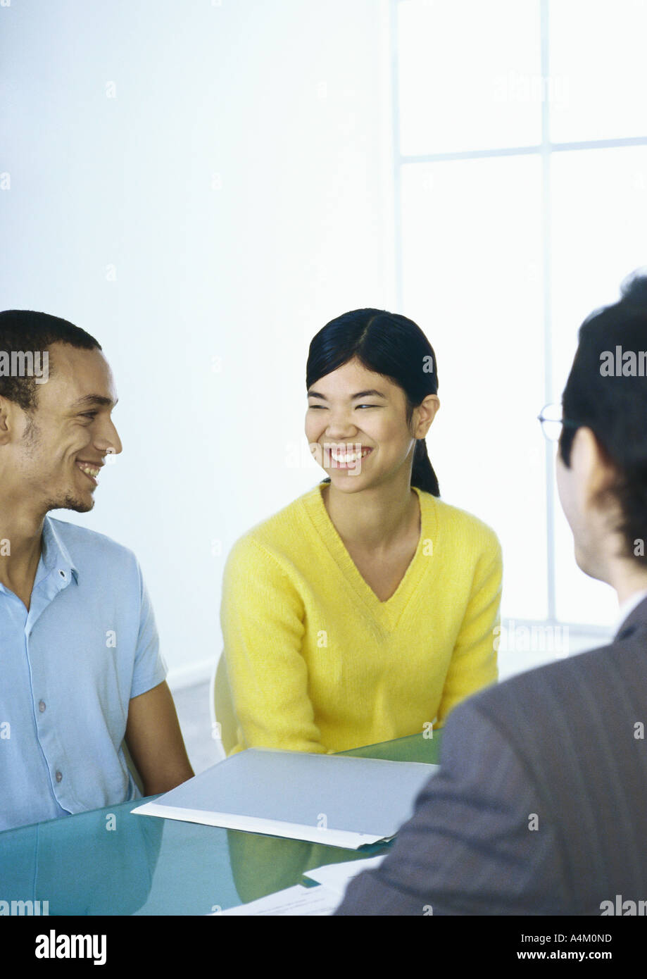 Man and woman smiling, sitting across table from businessman Stock ...