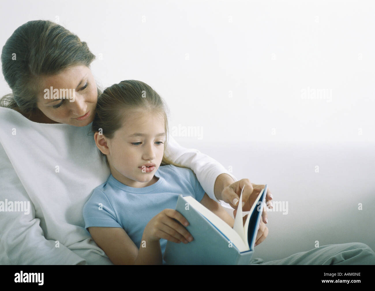 Woman and girl reading book together Stock Photo - Alamy