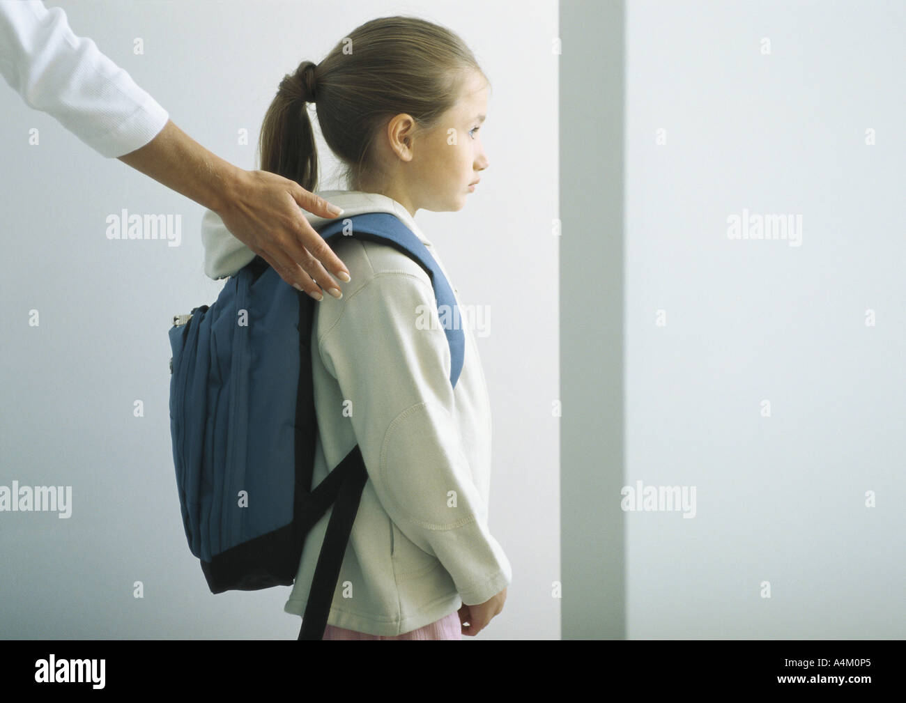 Woman's hand on shoulder of girl with backpack Stock Photo - Alamy