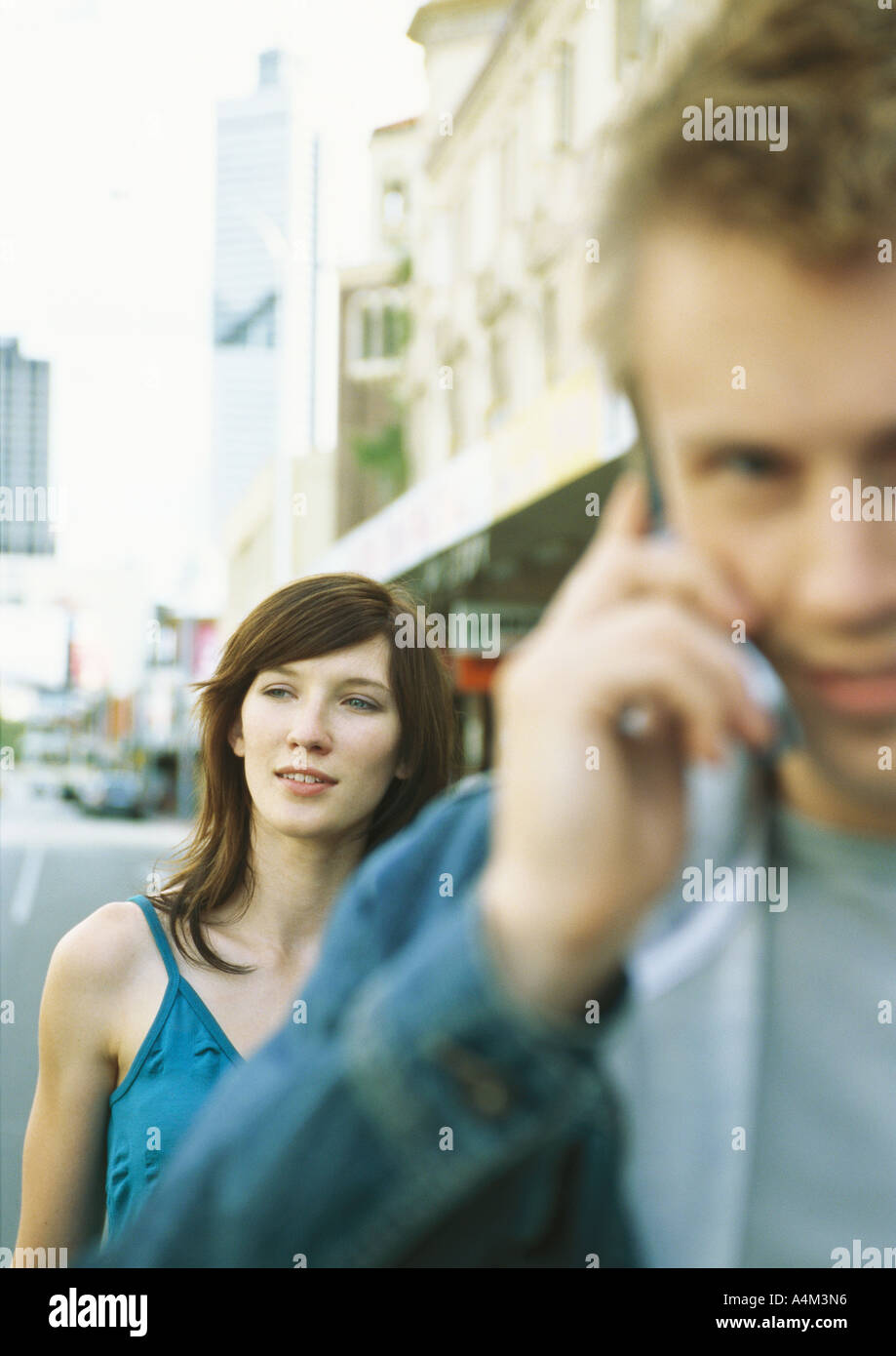 Young couple in city, man using cell phone Stock Photo - Alamy