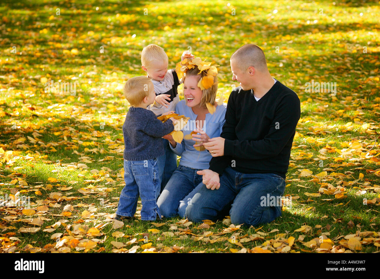 Children sprinkle leaves on mom Stock Photo - Alamy