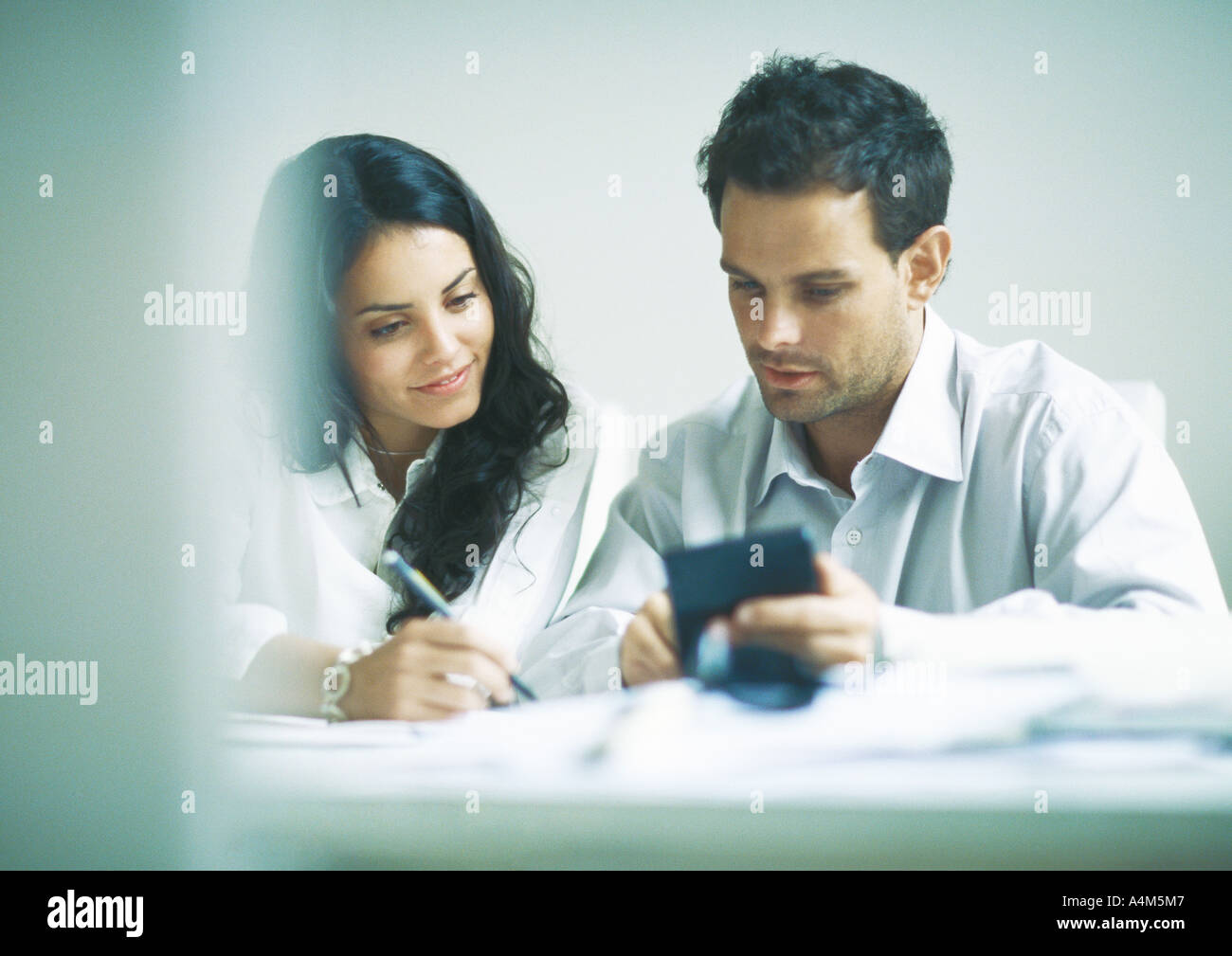 Young adults examining documents, calculating Stock Photo - Alamy