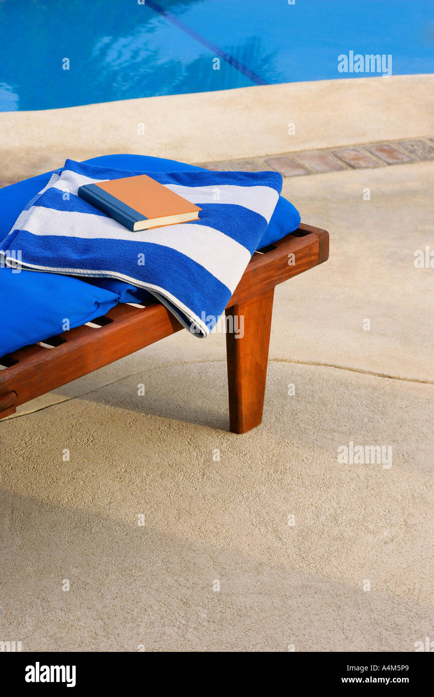 Towel chair and book by pool Stock Photo - Alamy