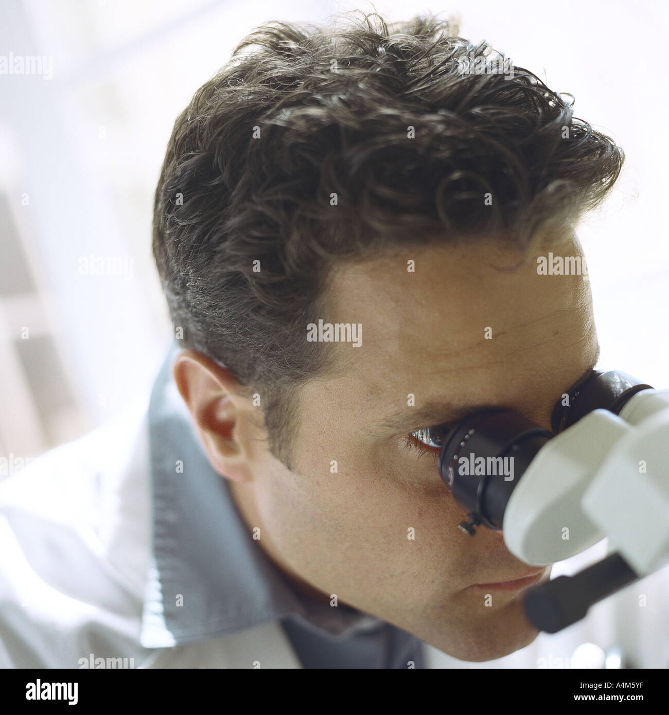 Doctor looking through microscope Stock Photo - Alamy