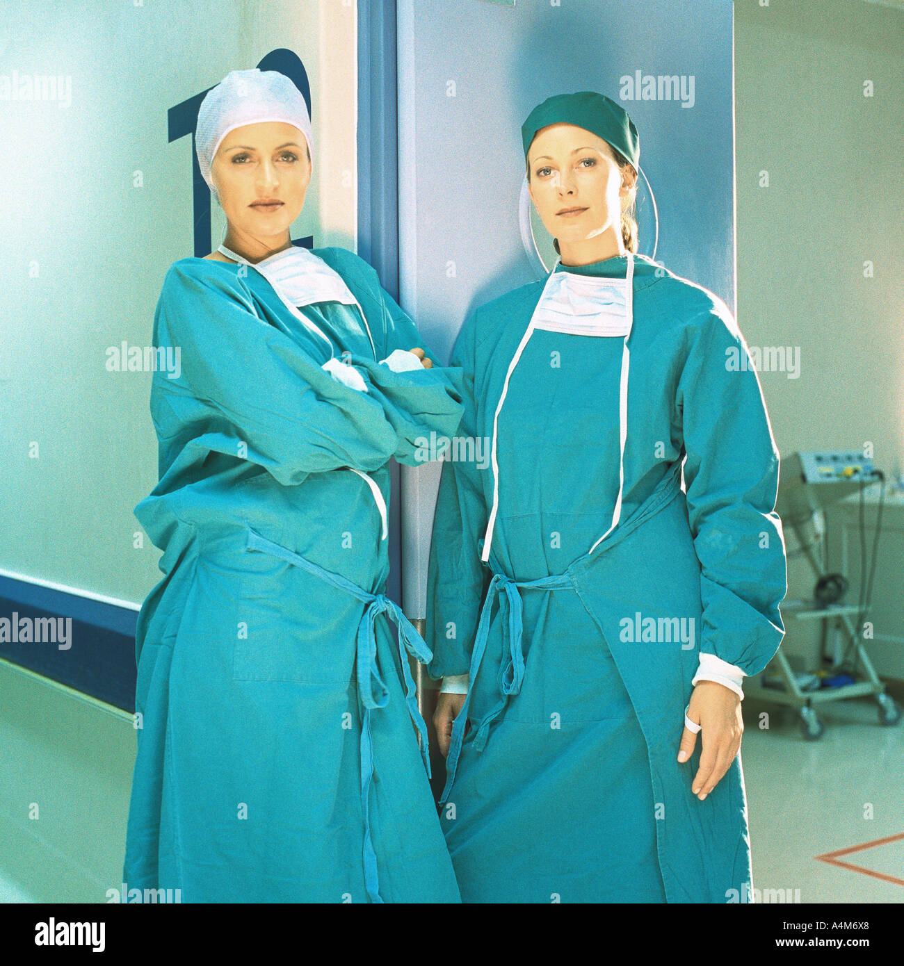 Two female doctors in operating gowns, leaning against doorframe Stock ...