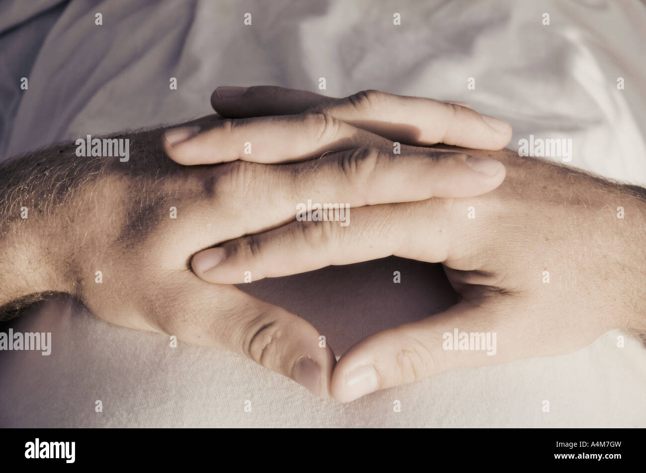 Hands of a resting man interlocked over his stomach Stock Photo - Alamy