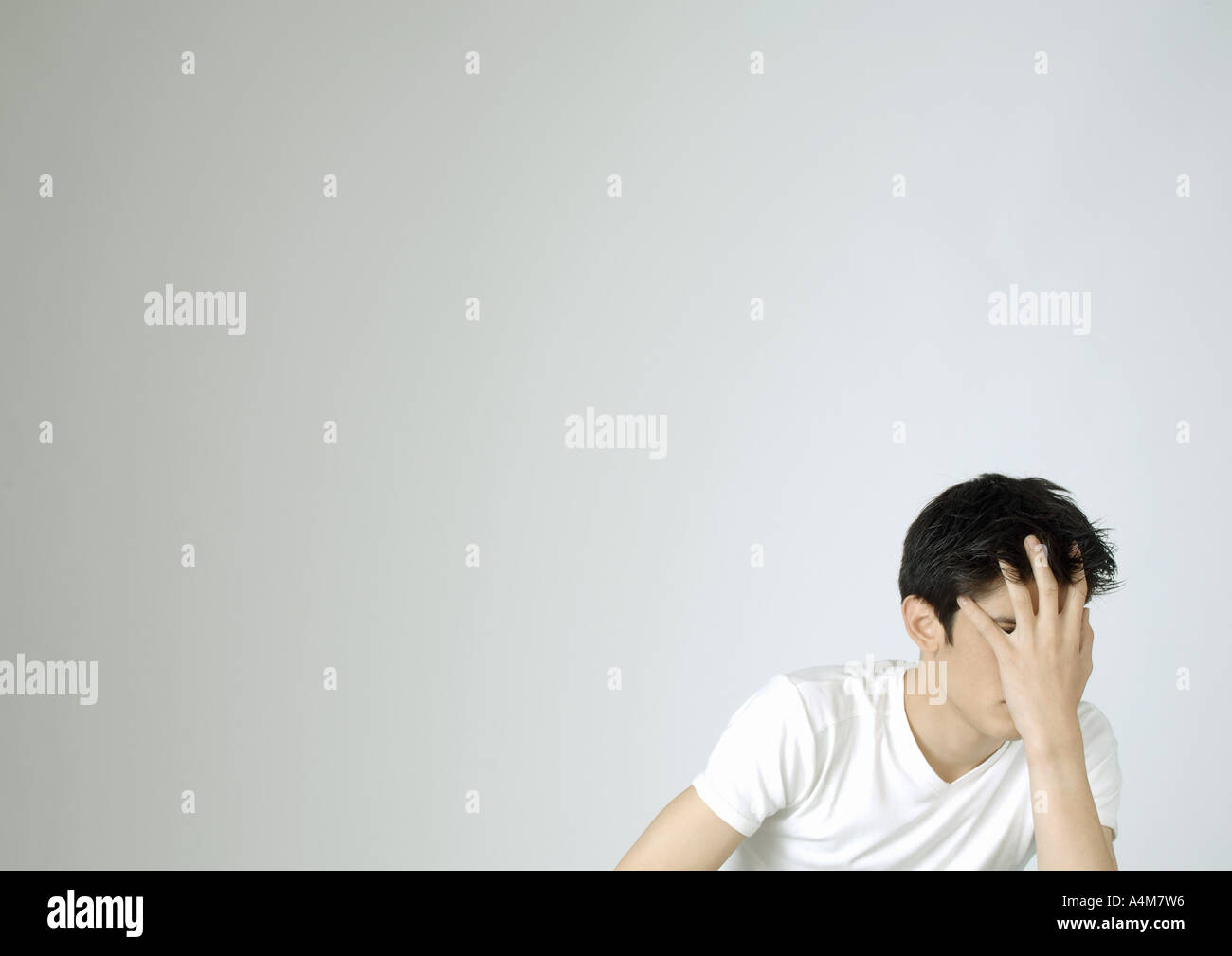 Young man covering face with hand Stock Photo - Alamy