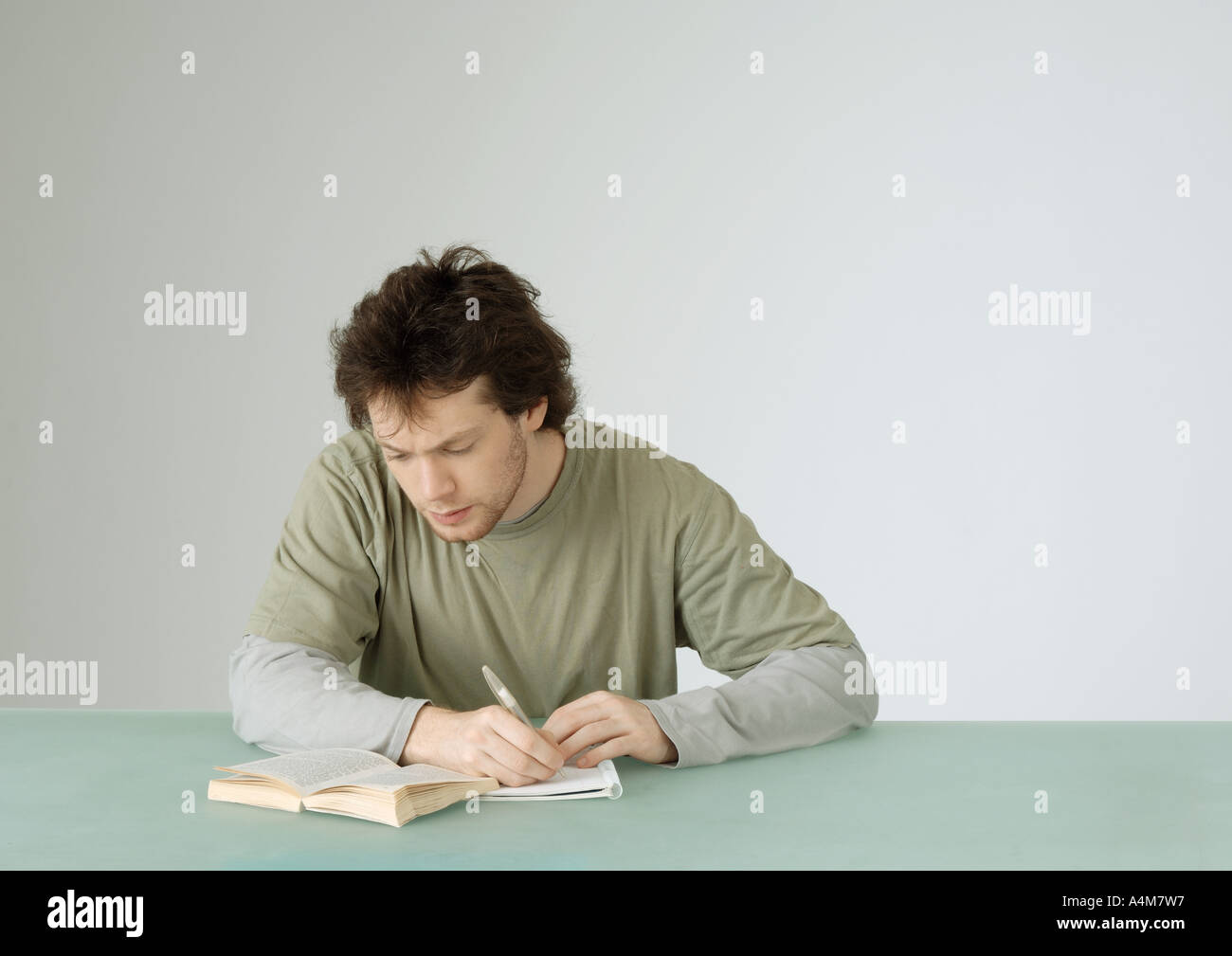 Young man sitting with open book, taking notes Stock Photo - Alamy
