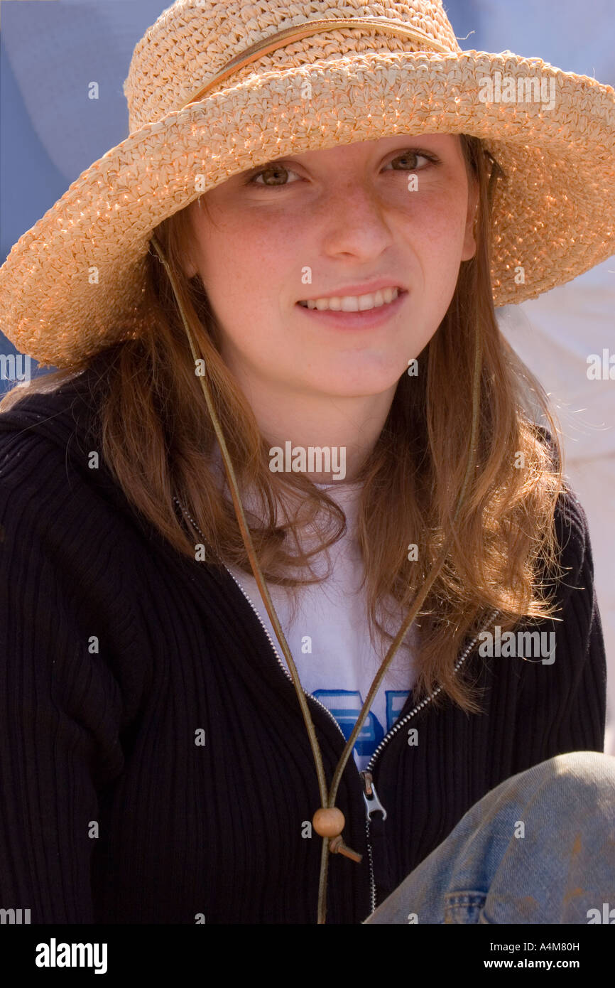 A sweet young teenaged girl wearing a straw hat, smiling shyly for the ...